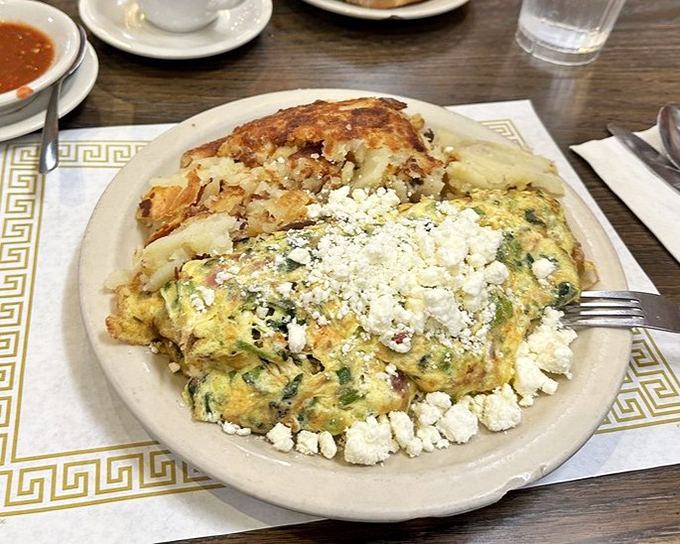 This isn't just an omelet &ndash; it's a Greek masterpiece with feta crumbles standing guard around fluffy eggs and a side of potatoes that didn't come to play.
