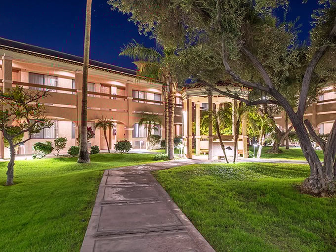 La Fuente Inn & Suites offers a palm-lined oasis for weary travelers. The evening lighting transforms this affordable accommodation into a tranquil desert retreat.