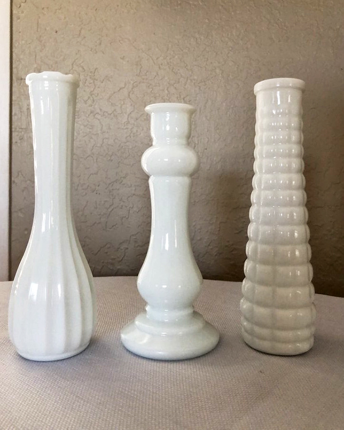 Milk glass vases standing like elegant ghosts of dinner parties past. Mid-century chic that turns any grocery store flowers into an arrangement.