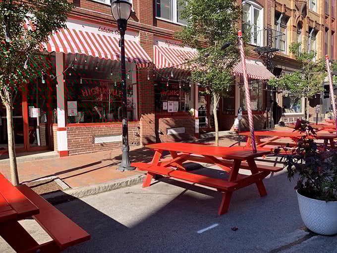 Red picnic tables under dappled sunlight offer the perfect stage for your lobster feast. Urban dining with a side of fresh air.