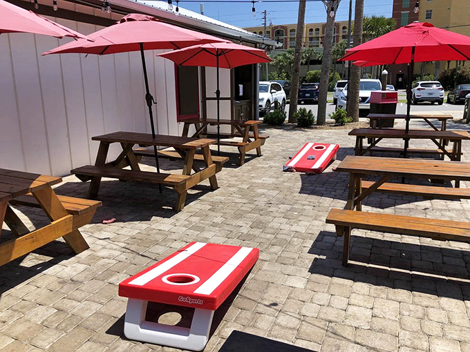 Outdoor seating done right: picnic tables, red umbrellas, and even cornhole boards&mdash;because seafood tastes better with a side of sunshine.