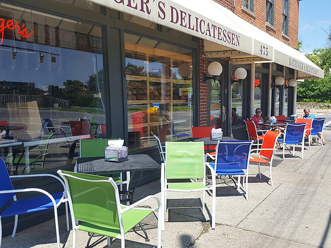 Colorful chairs line the sidewalk like a welcoming committee, inviting passersby to enjoy their towering sandwiches in the fresh air.