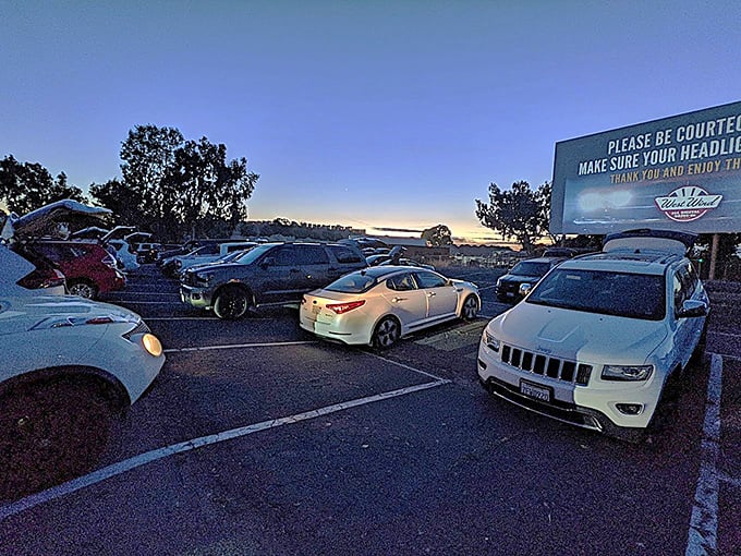 Cars gather like faithful pilgrims as dusk settles over the drive-in. Each vehicle contains its own private theater experience within a communal one.
