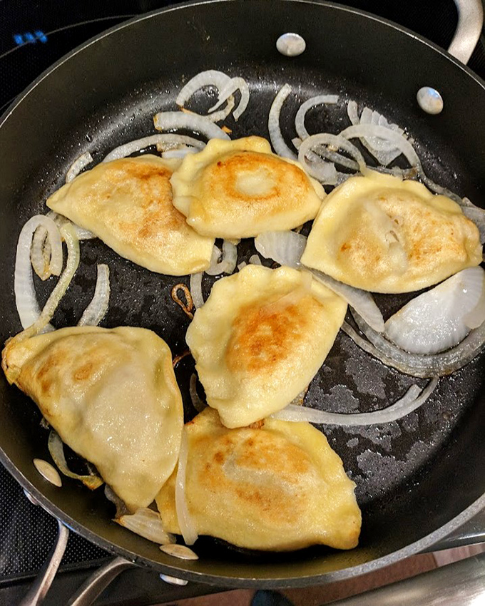 Pierogies achieving golden perfection in a bath of butter and onions. The sizzle is nature's most beautiful soundtrack.