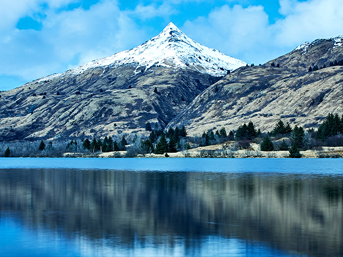 Pyramid Mountain reflects perfectly in crystal waters, creating the kind of double-take view that makes you question whether you're looking at reality or a screensaver.