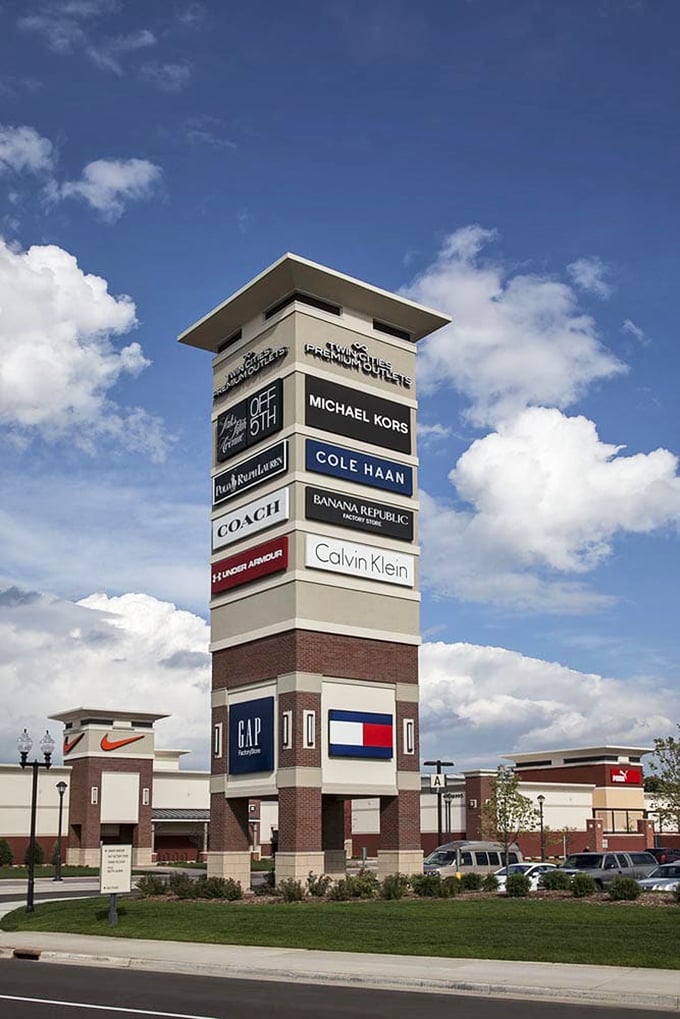 This towering brand beacon reaches skyward like a monument to retail glory, showcasing the impressive roster of designer names awaiting inside.