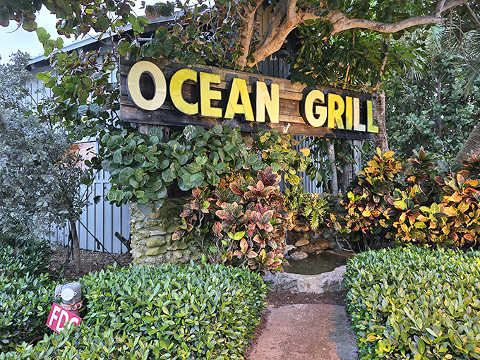 The Ocean Grill sign, nestled among lush greenery, welcomes hungry visitors like an old friend. Your taste buds' adventure begins here.