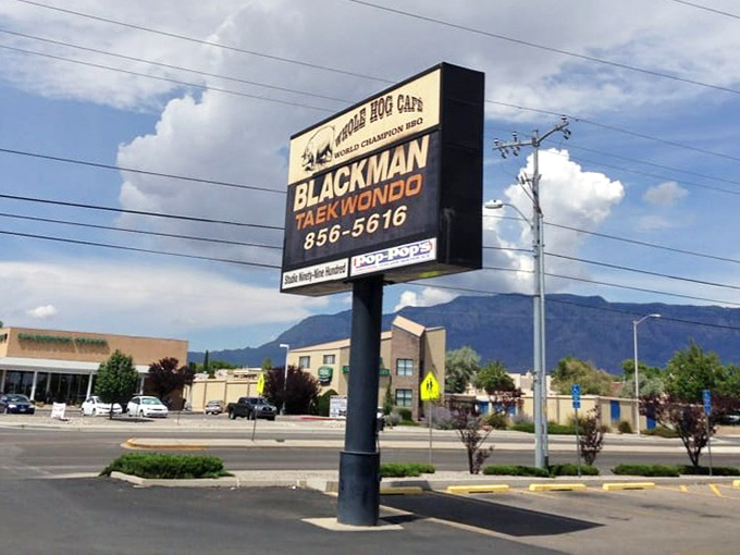 The sign standing tall against the New Mexico sky, a beacon of hope for the BBQ-deprived traveler with mountains as its backdrop.