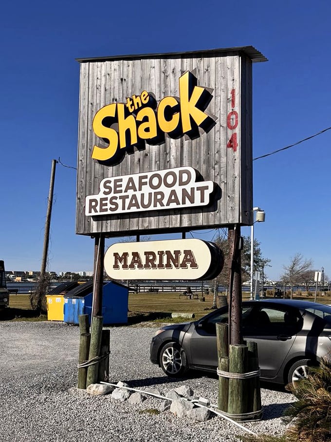 The weathered wooden sign stands like a beacon for hungry travelers – follow it to seafood salvation.
