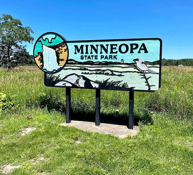 The vintage-style park sign welcomes visitors with retro charm. That blue waterfall icon has launched thousands of road trips.