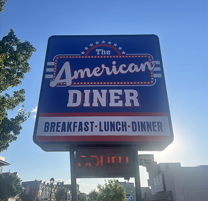 The American Diner sign stands proud against blue skies. Like the Statue of Liberty for hungry travelers, it promises freedom from cooking and the pursuit of happiness through pancakes.