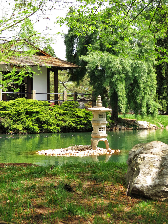 A stone lantern rises from the water like a miniature lighthouse, guiding visitors through the garden's peaceful landscape. Traditional craftsmanship meets timeless design.