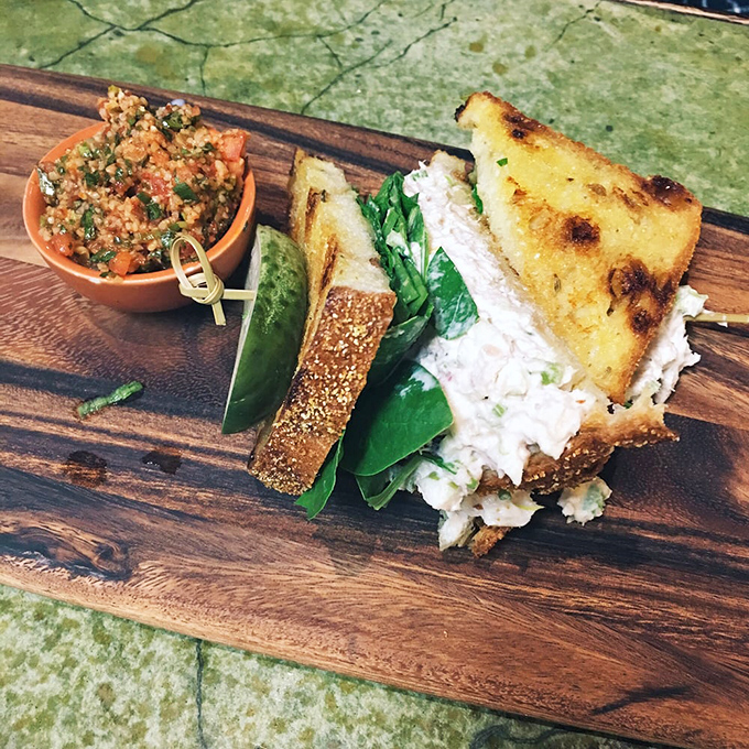 Not just a sandwich, but an edible still life&mdash;house-made tuna salad with a side of vibrant tabbouleh on a wooden board that doubles as a canvas.