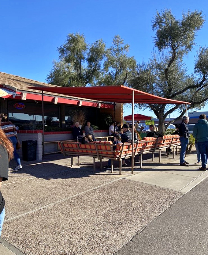 The outdoor waiting area where strangers become temporary friends, united by the shared anticipation of what awaits inside.