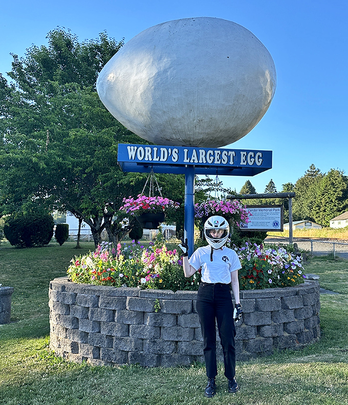Summer brings vibrant hanging baskets and colorful flowers to the egg monument's base, creating a garden-like setting for this quirky roadside wonder.