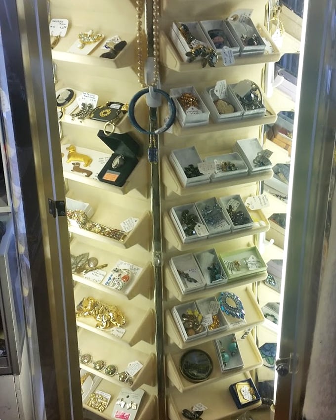 Vintage brooches and beaded treasures sparkle under display lights&mdash;grandmother's jewelry box, but make it a whole cabinet.