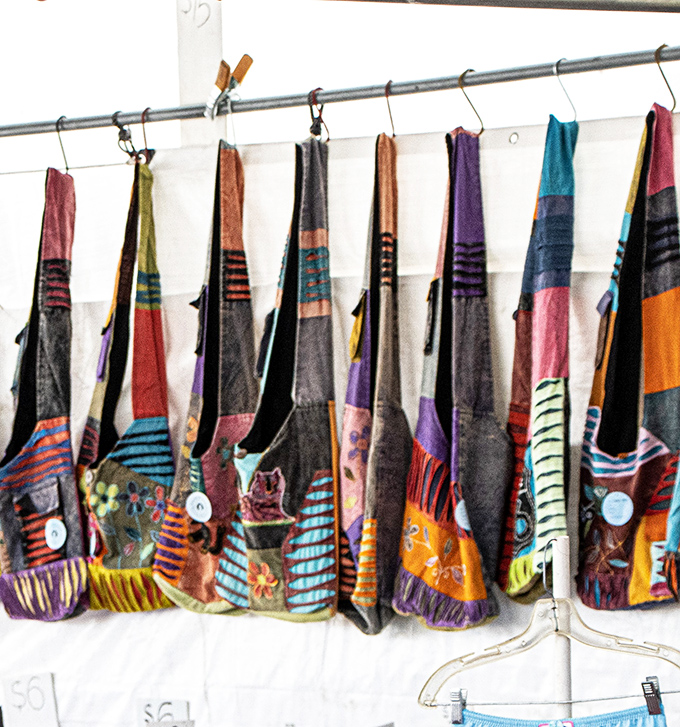 Colorful patchwork bags hang like exotic fruit, each one a portable art piece waiting to carry your market treasures home.