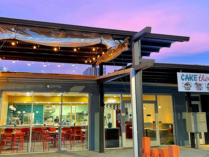 Sunset casts a magical glow on Cake Thieves' exterior. The string lights hint at the warm welcome waiting inside this unassuming pastry paradise.