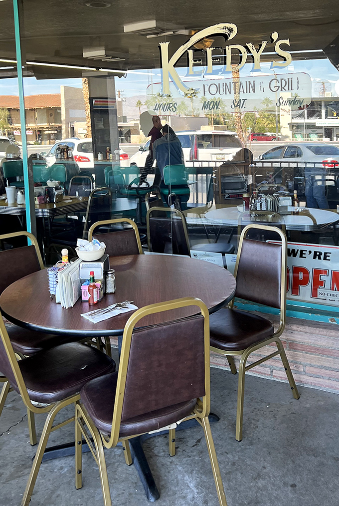 Through these windows, Palm Desert life unfolds—palm trees sway outside while inside, the ritual of American dining continues unchanged.