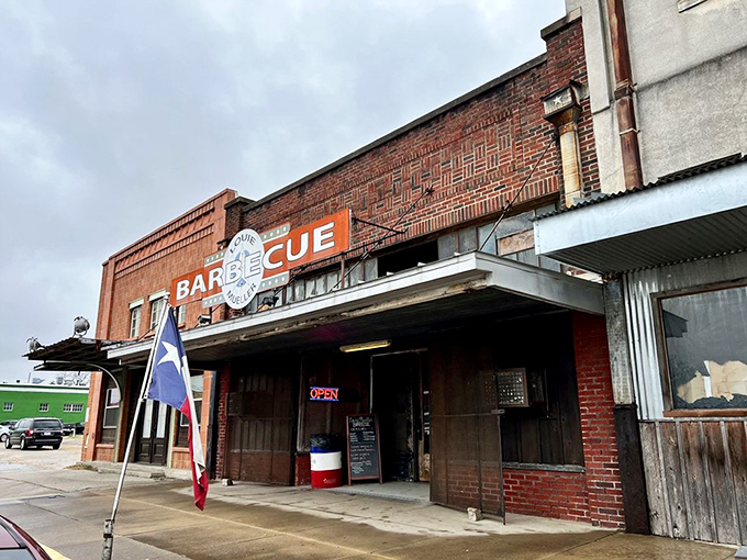The exterior view with Texas flag flying says everything you need to know: this is authentic, proud, unapologetic barbecue.