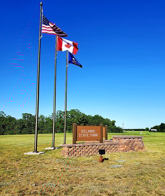 Three flags stand tall at the park entrance, a colorful welcome committee against the impossibly blue North Dakota sky.