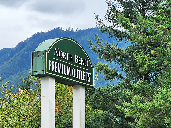 The gateway to bargain paradise. North Bend Premium Outlets' sign stands against a backdrop of mountains that remind you: the best views in Washington aren't free.