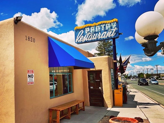 The adobe exterior with its distinctive blue awning &ndash; Santa Fe's architectural tradition meets classic American diner in perfect harmony.