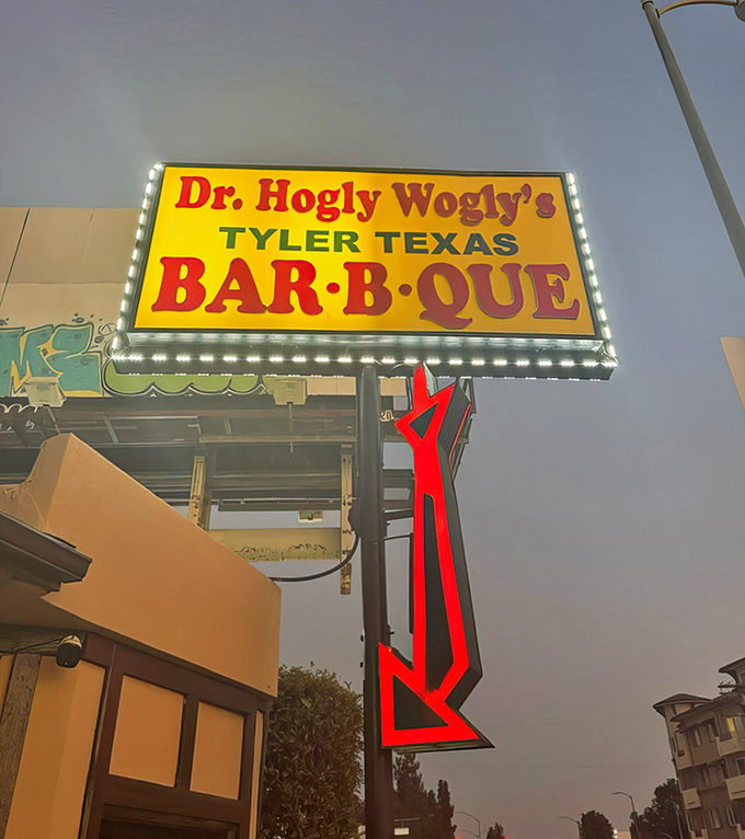 By night, the sign glows like a barbecue lighthouse, guiding hungry souls through the darkness toward smoky salvation.