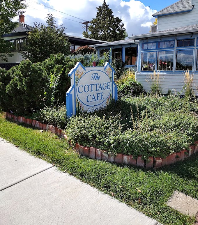 The blue Cottage Cafe sign nestled among well-tended shrubs serves as a beacon for sandwich seekers throughout Casper and beyond.