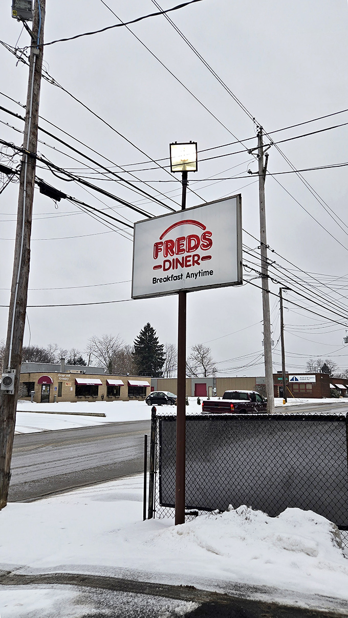 In winter's grip, Fred's sign glows like a beacon for the breakfast-deprived, promising warmth, coffee, and pancakes that could make a snowman weep.