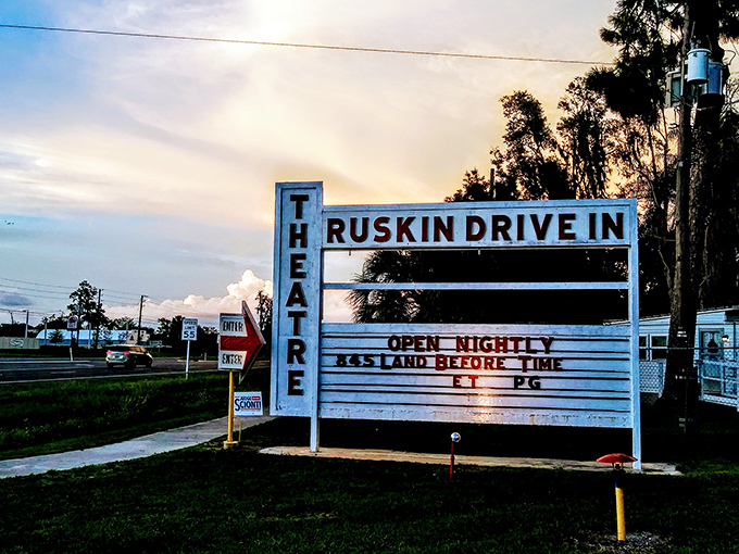 The roadside marquee announces nightly showings to passing cars, a glowing invitation to trade digital isolation for communal entertainment under the stars.