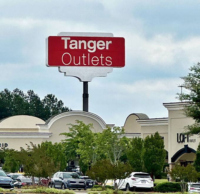 The iconic red Tanger sign rises above the trees&mdash;a retail North Star guiding dedicated shoppers to their discount destination.