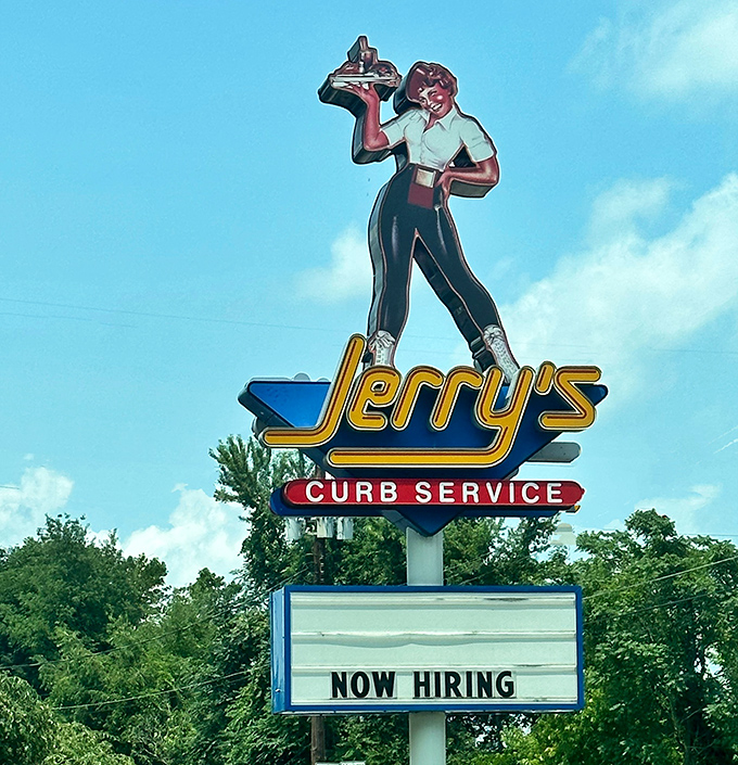 The vintage carhop signage featuring a server with tray evokes a simpler time, when service came with a smile and dinner came balanced on a tray at your car window.