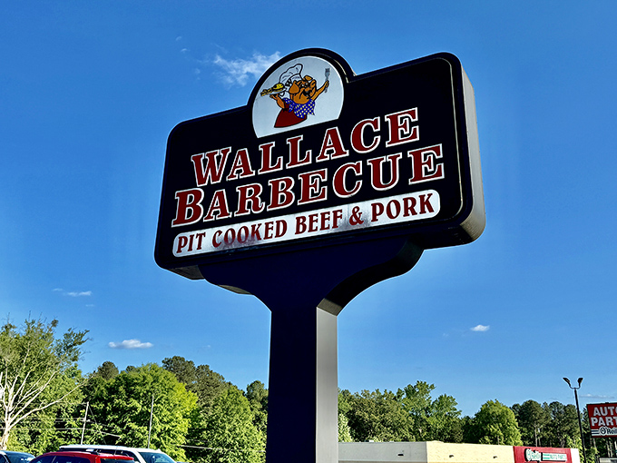 The sign rises above the trees like a beacon of barbecue hope, promising pit-cooked perfection to travelers wise enough to exit the highway for something truly memorable.