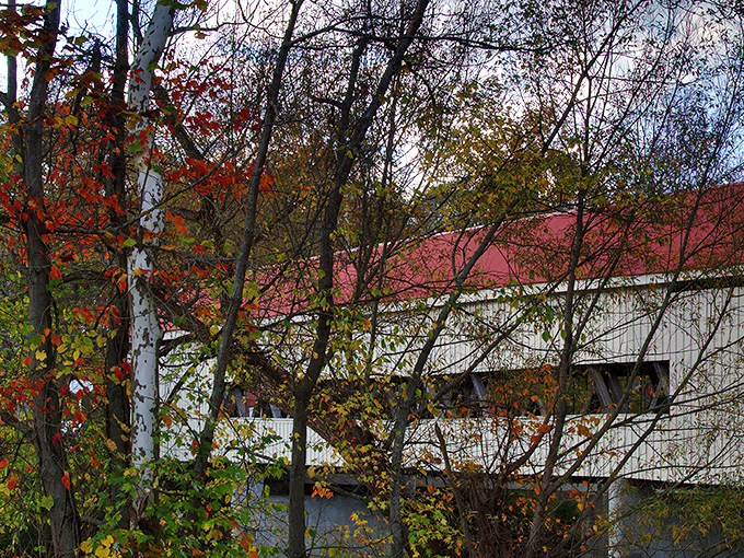 Fall foliage creates the perfect frame for the white bridge with its distinctive red roof&mdash;a photographer's dream in Ashtabula County's countryside. 