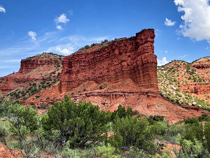 Towering red cliffs that look like nature's skyscrapers, standing majestically against the brilliant blue Texas sky.