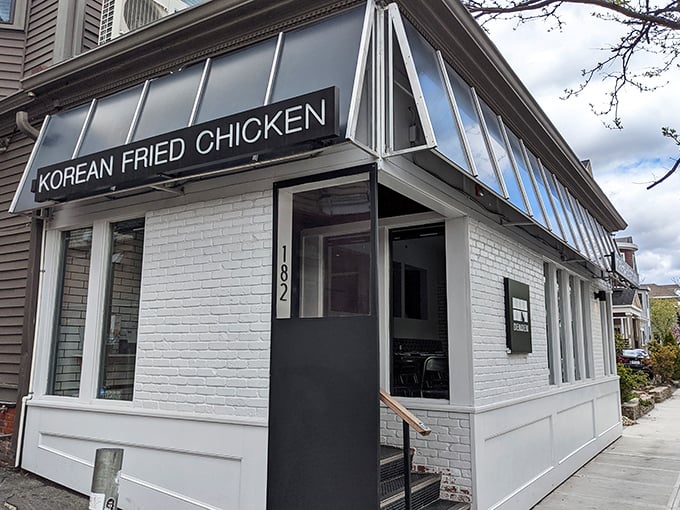 The sleek white exterior of Den Den Korean Fried Chicken promises crispy delights within &ndash; like finding a treasure chest of crunch in Providence.