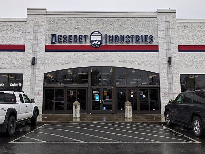 The white facade of Deseret Industries stands like a treasure chest waiting to be opened. Blue lettering promises adventures in secondhand shopping.