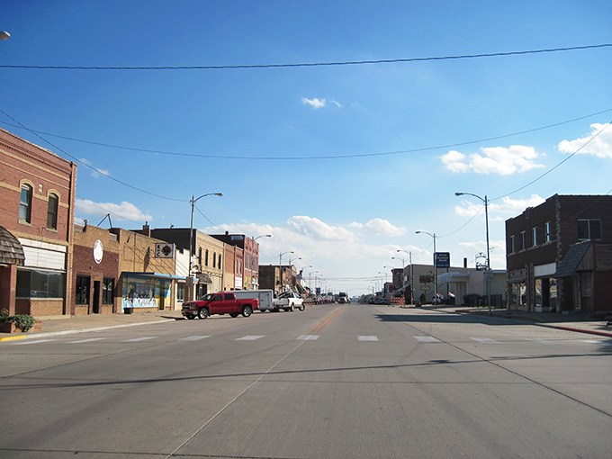 Main Street in Hoisington stretches toward the horizon, where brick buildings and blue skies create that perfect small-town postcard scene.