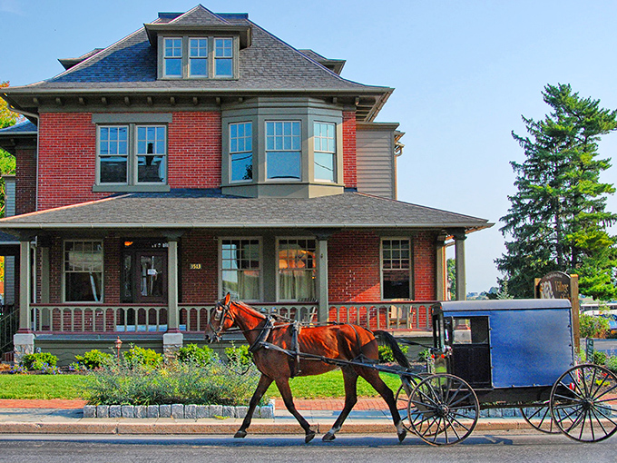 A classic red brick home with a horse and buggy passing by - Intercourse's timeless charm captured in a single frame.