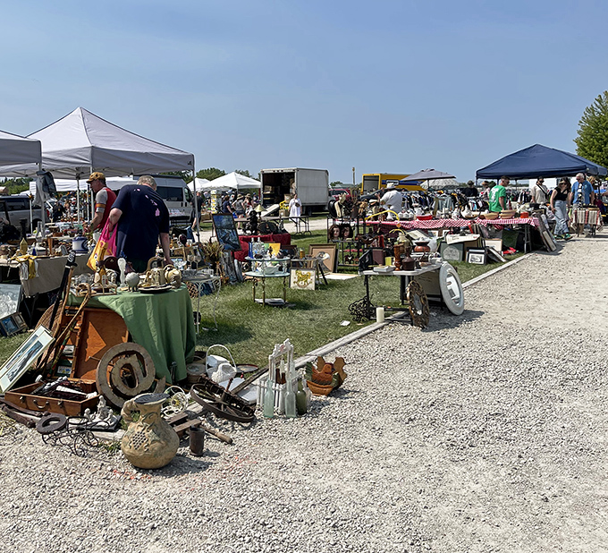 Treasure hunters browse outdoor displays at Kane County Flea Market, where antiques and collectibles fill tables under summer skies.