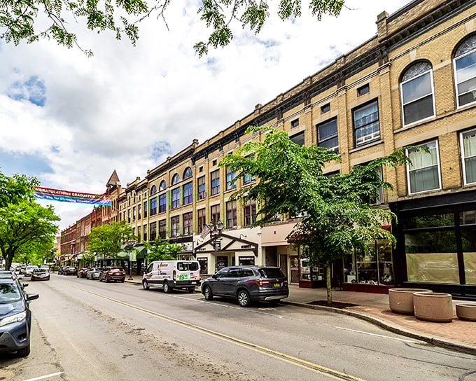 Historic charm meets small-town affordability in Oneonta's inviting Main Street, where brick buildings house local businesses beneath a banner of community pride.