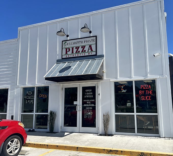 The clean white exterior of Palmetto Pointe Pizza promises New York authenticity hiding behind those unassuming doors.