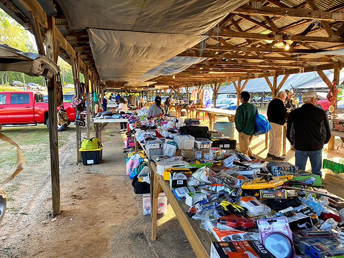 Treasure hunters browse rustic wooden tables under open-air sheds at Pickens County Flea Market. Every table tells a different story!