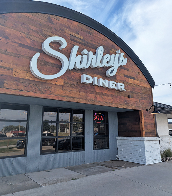 The curved wooden facade of Shirley's Diner stands like a beacon of comfort food promise against the Nebraska sky.