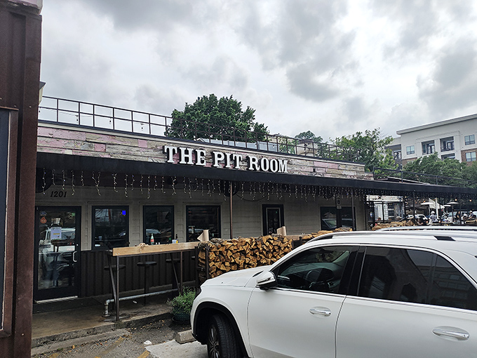 The Pit Room's exterior showcases stacked firewood, hinting at the authentic smoke flavor waiting inside this Houston barbecue destination.