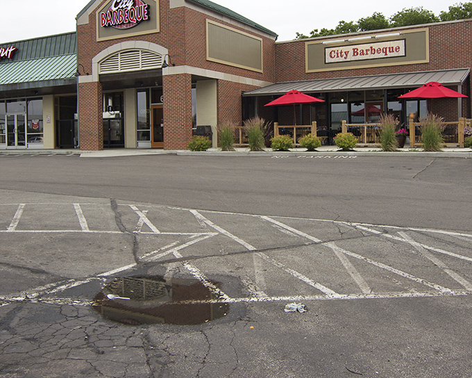 Red umbrellas dot the patio like cherry tops on a sundae. City Barbeque's welcoming storefront promises meaty treasures within.