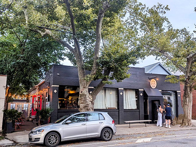 Tall trees frame this neighborhood gem, where pizza dreams come true beneath a deceptively simple black facade.