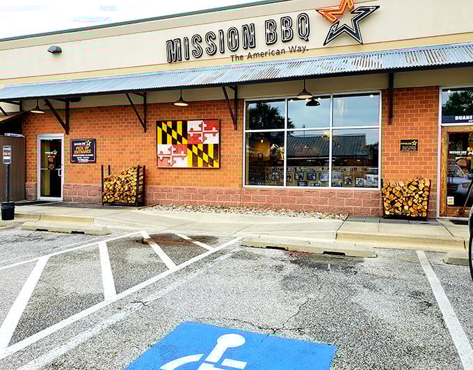 The Maryland flag proudly displayed at Mission BBQ reminds you that great barbecue transcends state lines. Those woodpiles hint at smoky treasures inside.