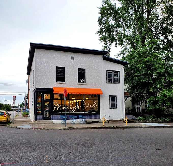 Sunlight bathes Marty's Deli's white facade, where neighborhood sandwich dreams come true under that distinctive orange awning.